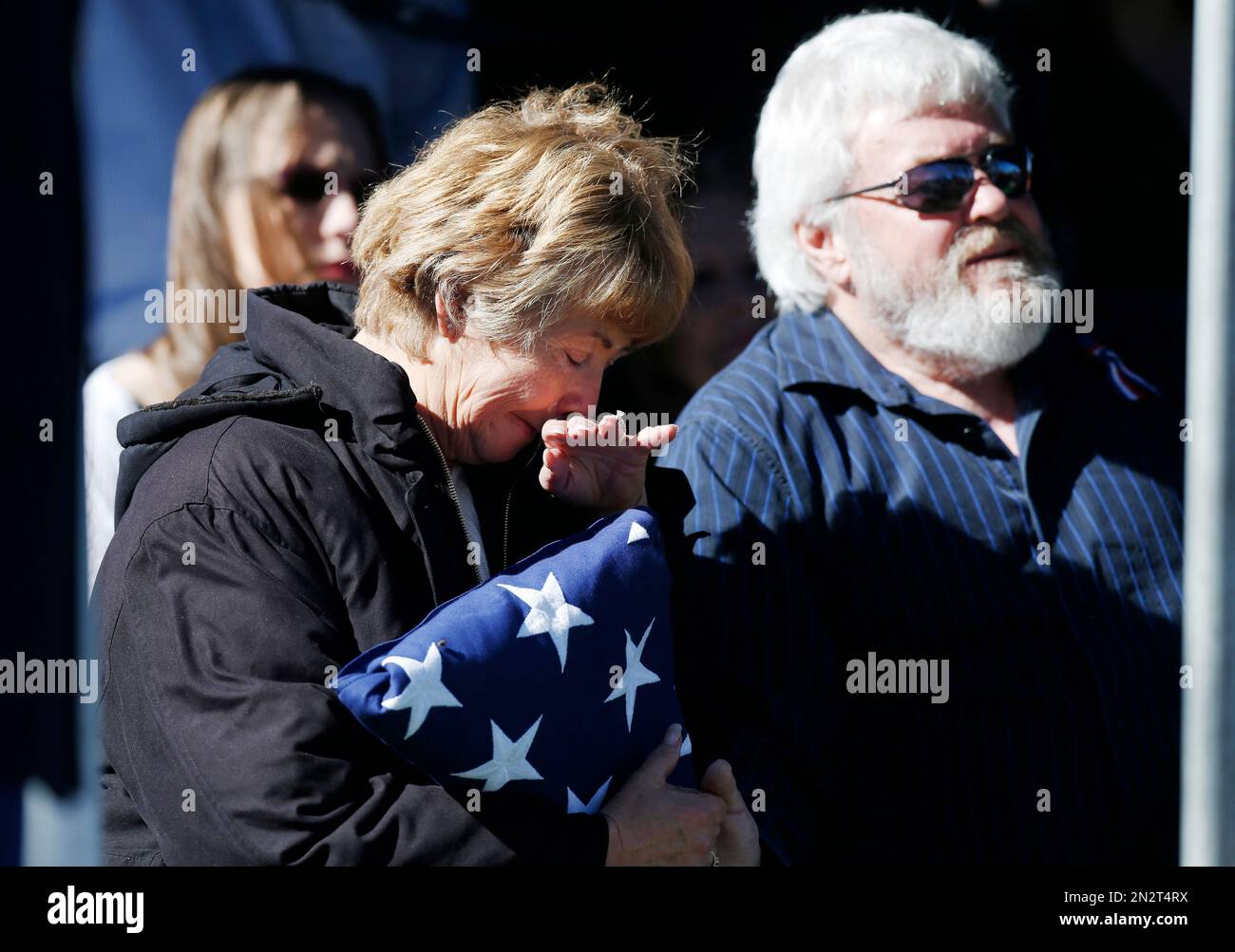 Joann Mueller, front, fights back tears during a funeral service for ...