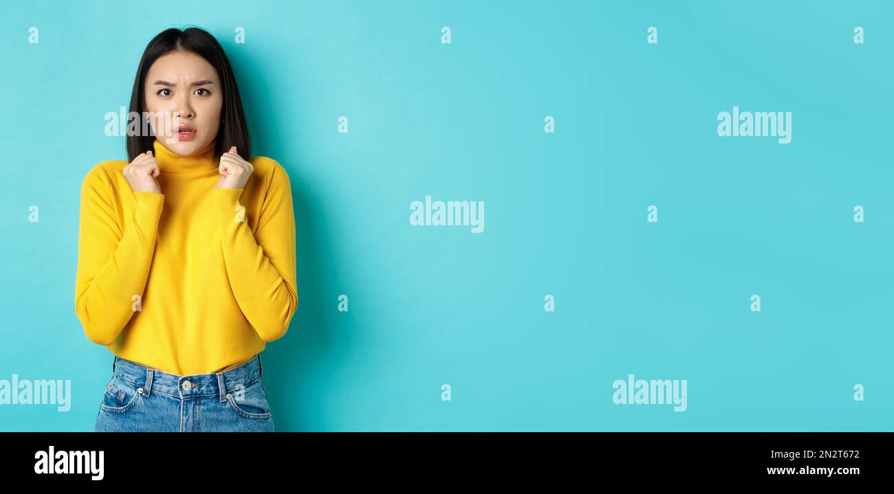 Image of worried asian woman with short dark hair, clench hands and ...