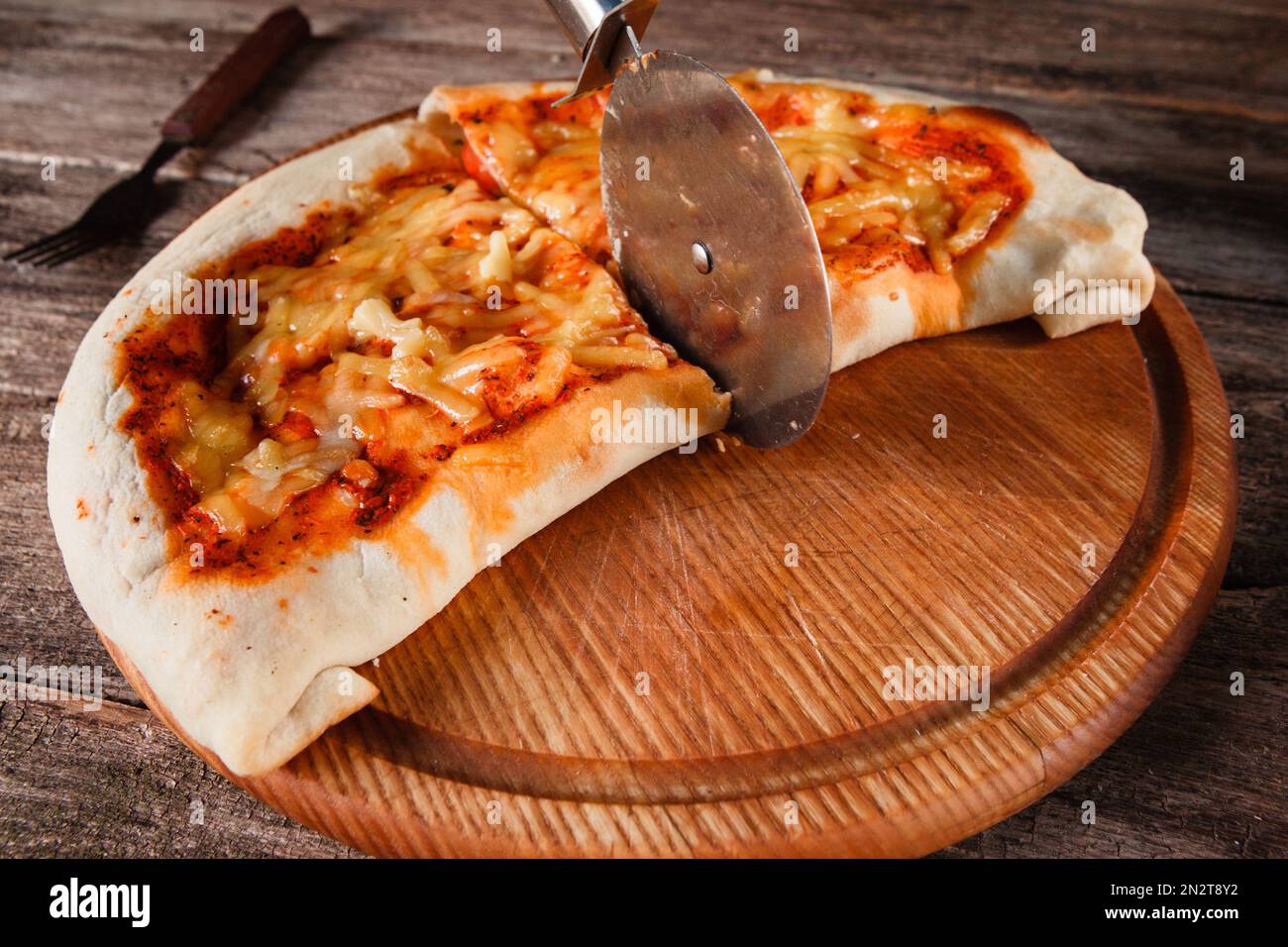 Pizza calzone cut with wheel on wooden platter Stock Photo - Alamy