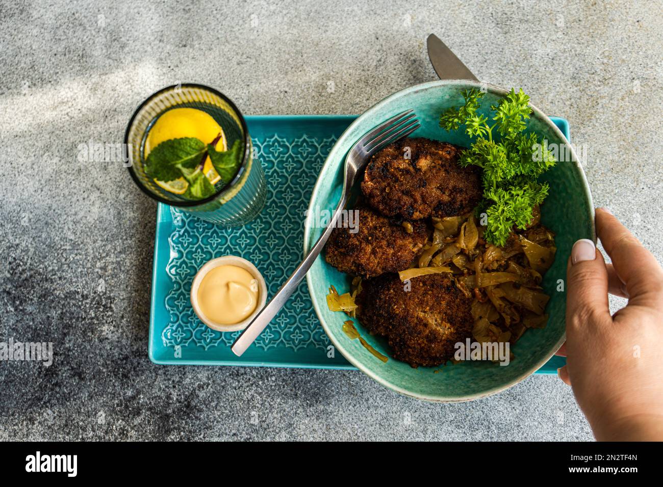 Overhead view of a woman eating pork cutlets with stewed cabbage ...