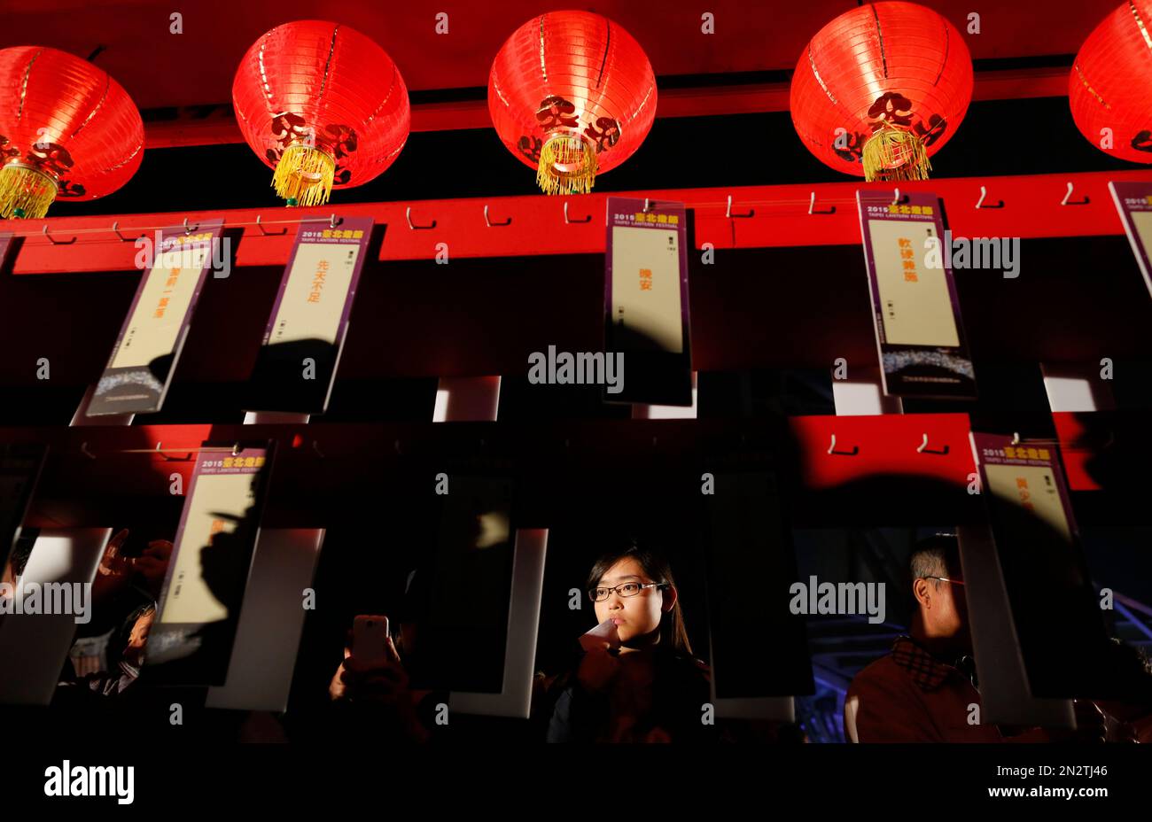 Visitors view lucky puzzles under a row of lanterns at the start of the ...