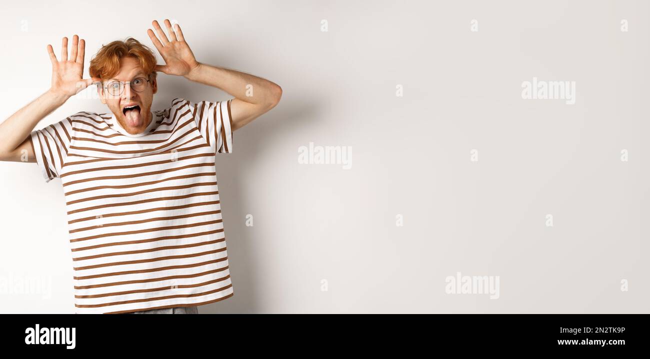 Funny young redhead man acting silly, showing tongue and mocking ...