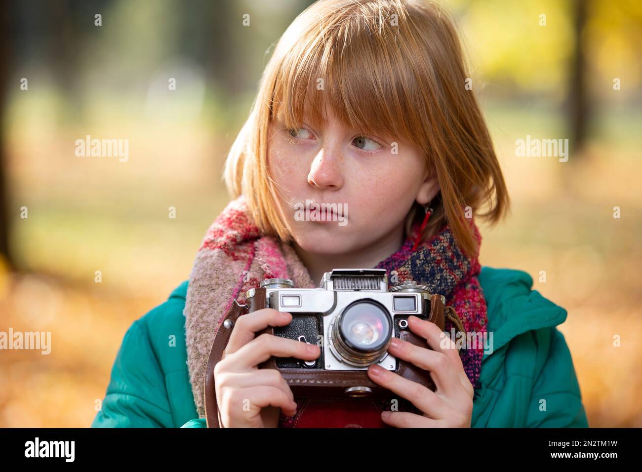 Little red-haired girl with a retro camera in the autumn park. Child photographer Stock Photo ...