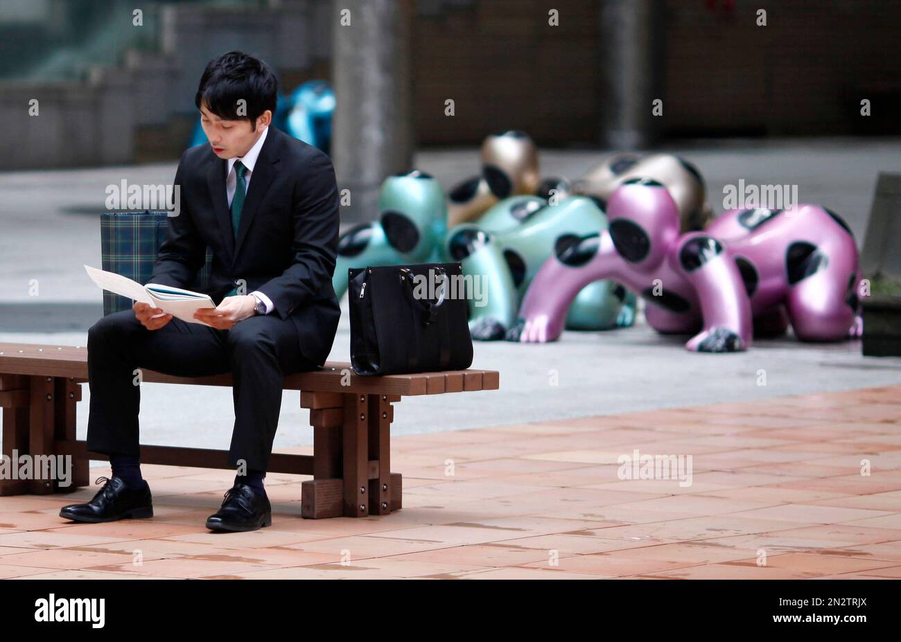 A man sits next to human-shaped objects in Tokyo Wednesday, March 4 ...