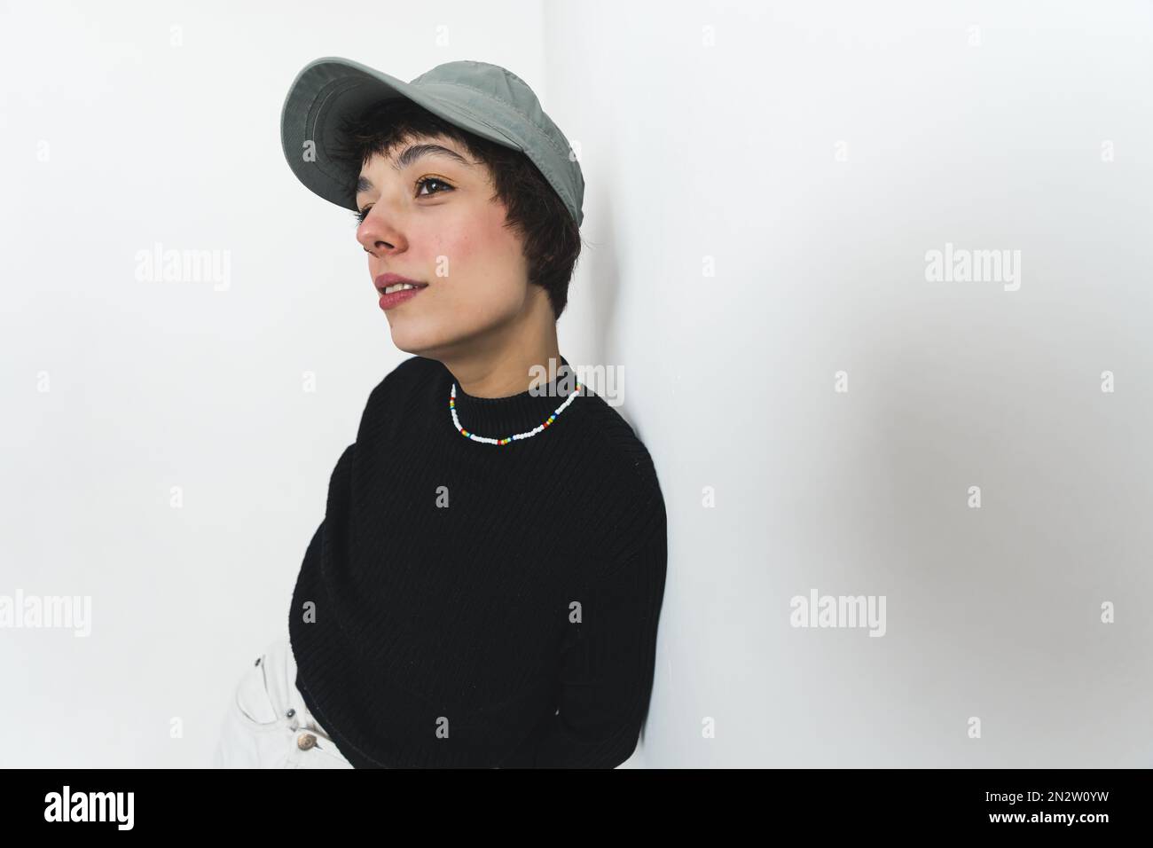 Cool stylish girl in gray cap on her head looking back and leaning over ...