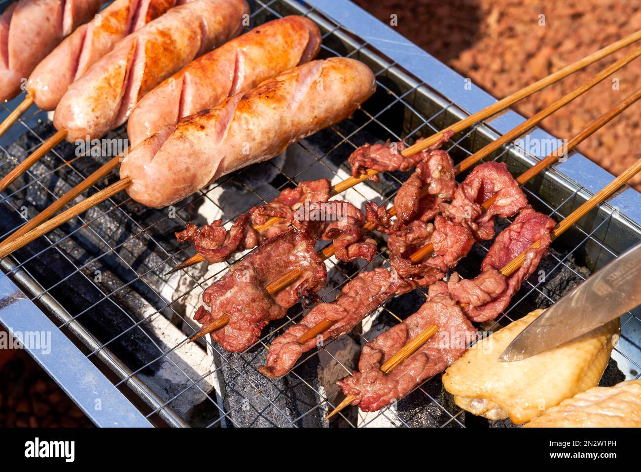 A person is grilling meat skewers in a picnic camping, delicious and ...