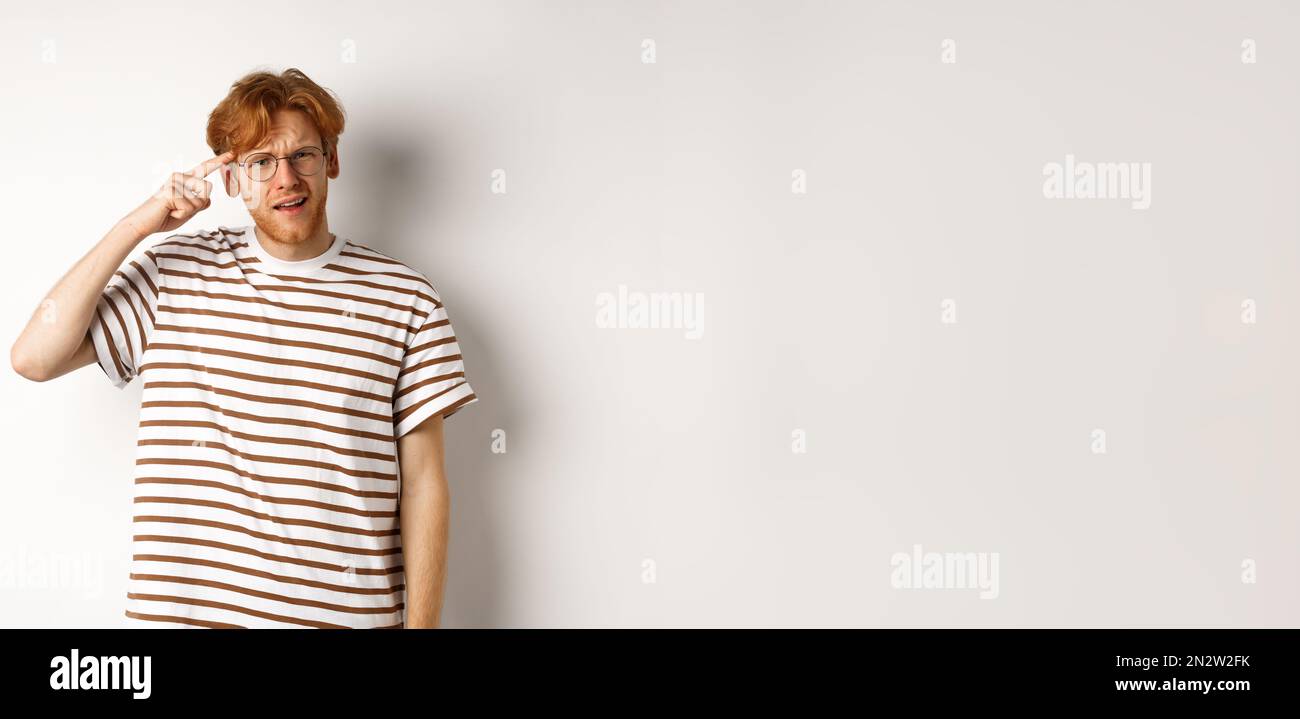 Annoyed Young Man With Red Hair Scolding Person For Being Stupid Pointing At Head And Staring
