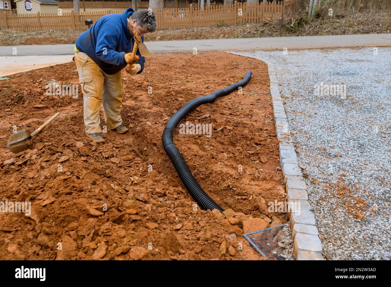 An employee digs trench to lay drainage pipe for catch rainwater during ...