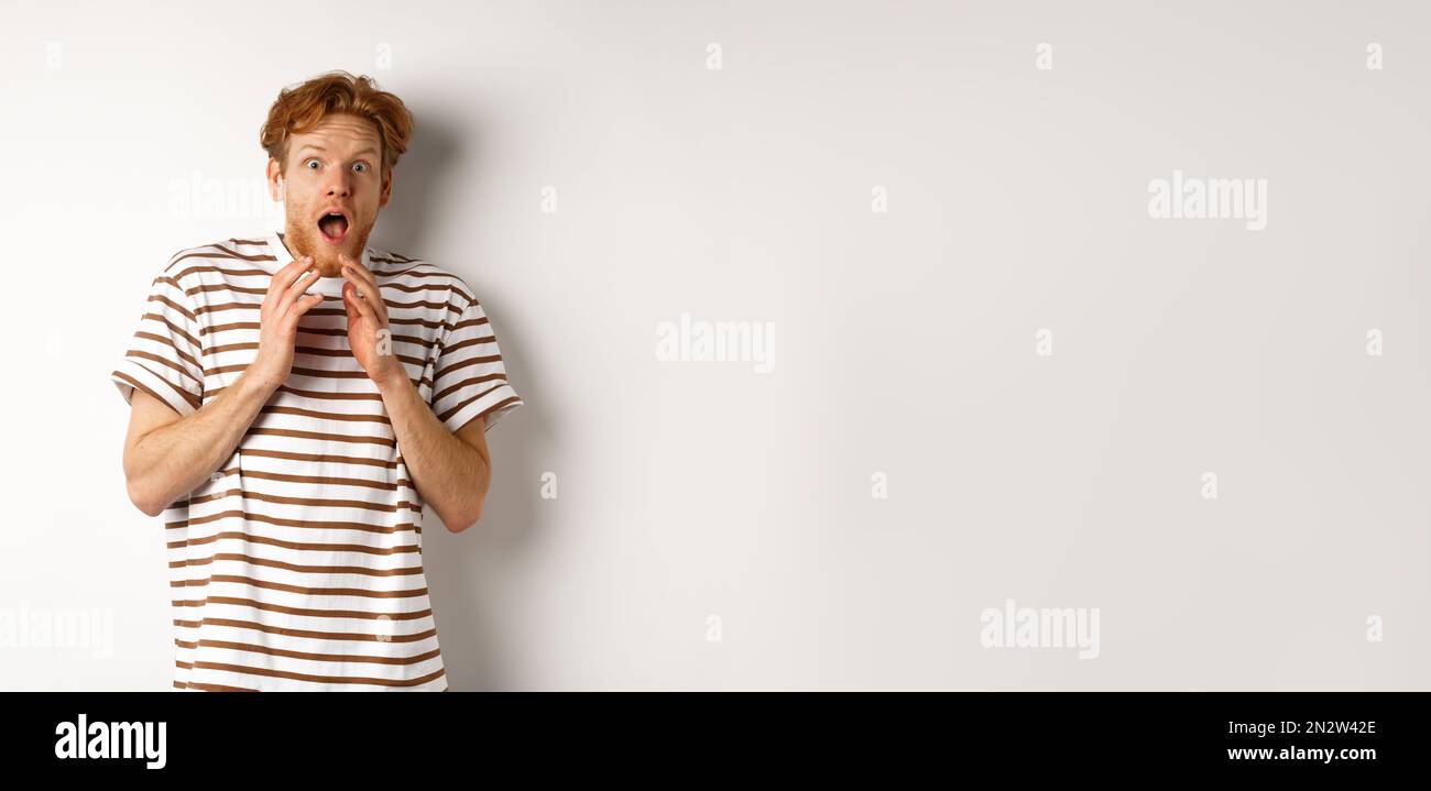 Timid young man with red hair, looking scared, jumping and screaming ...