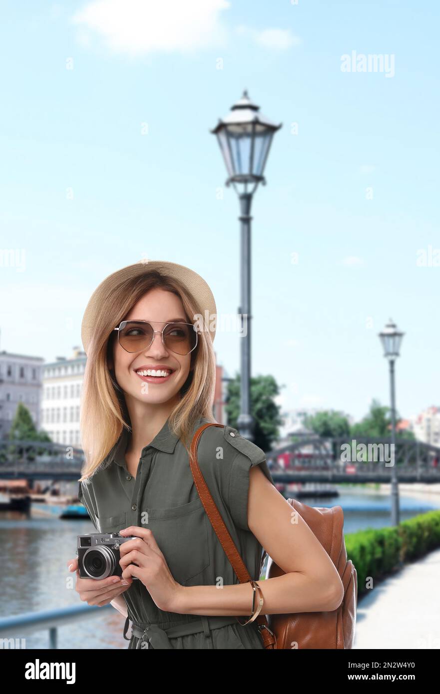 Happy traveler with backpack and camera in foreign city during summer ...