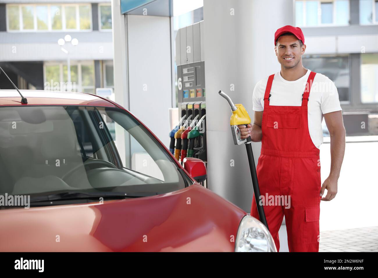 Worker with fuel pump nozzle near car at modern gas station Stock Photo ...