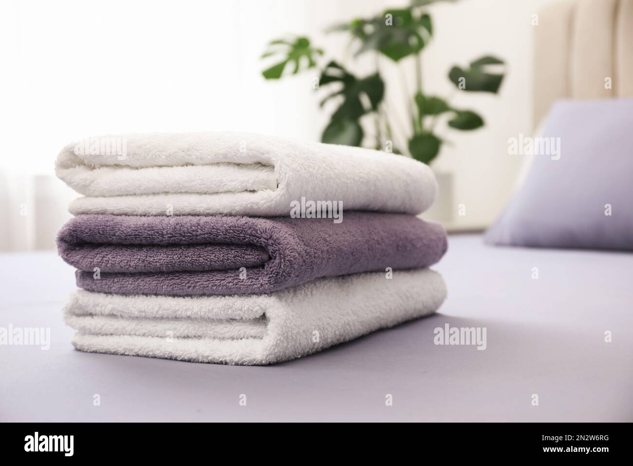 Stack of clean towels on bed indoors Stock Photo - Alamy