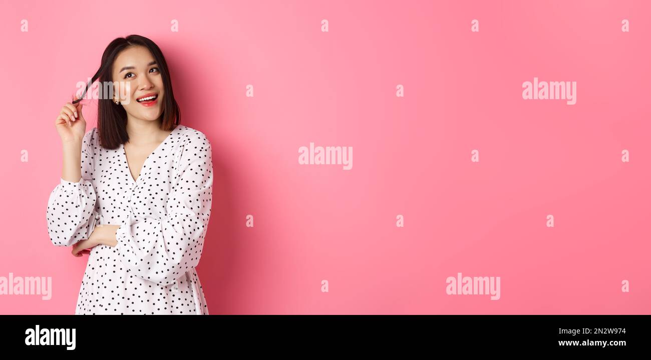 Dreamy cute asian girl thinking, imaging shopping and smiling, looking ...