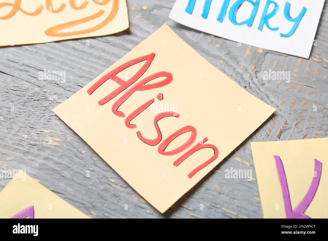 Paper sheet with baby name Alison on grey wooden table, closeup Stock ...