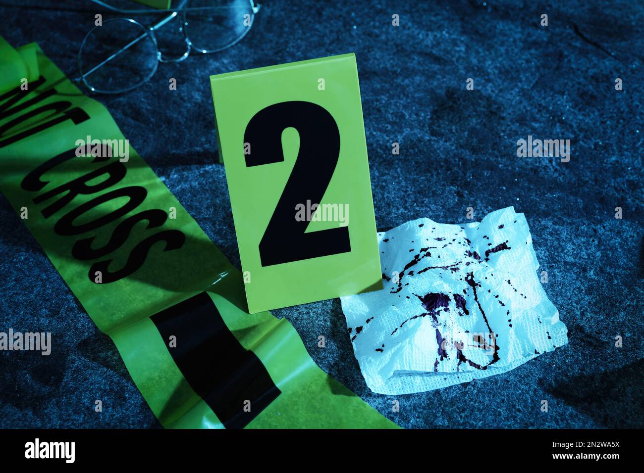 Bloody napkin, tape and crime scene marker on stone table at night ...