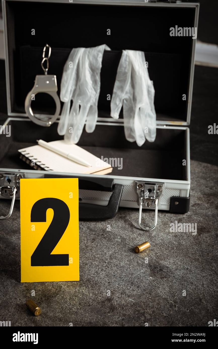 Crime scene marker and open case with police equipment on grey stone ...