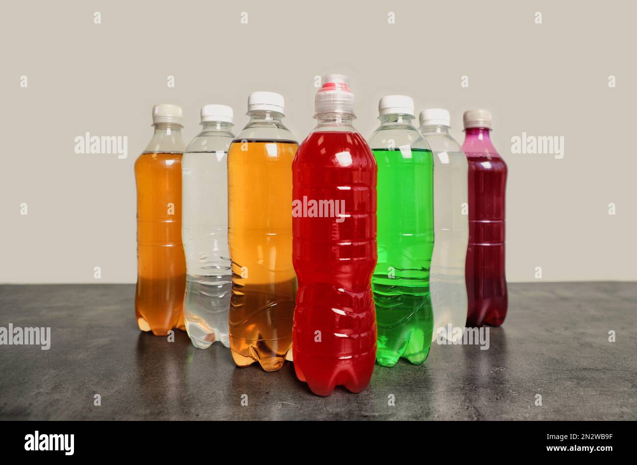 Bottles of soft drinks on table against grey background Stock Photo - Alamy