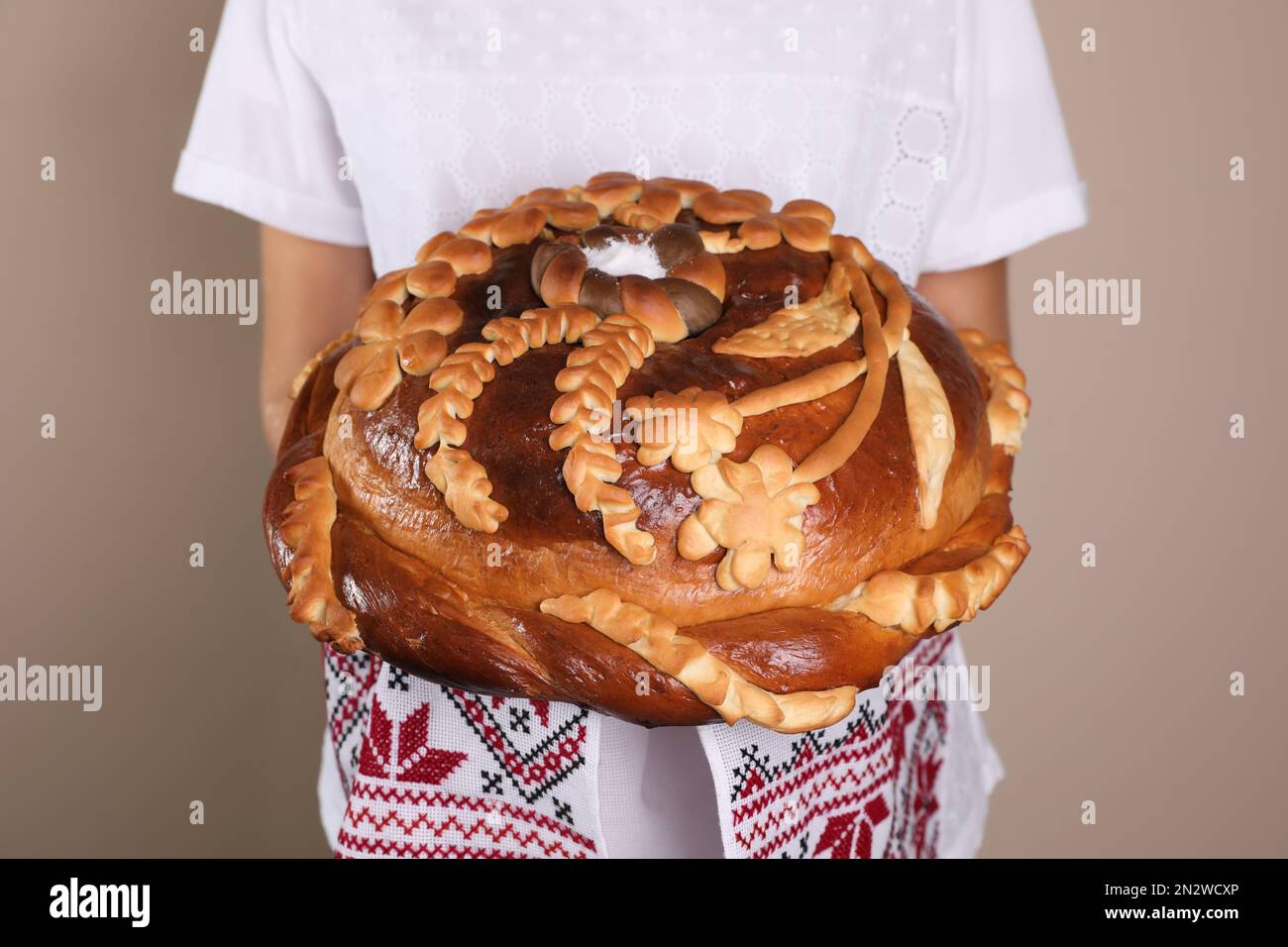 Woman with korovai on grey background, closeup. Ukrainian bread and ...