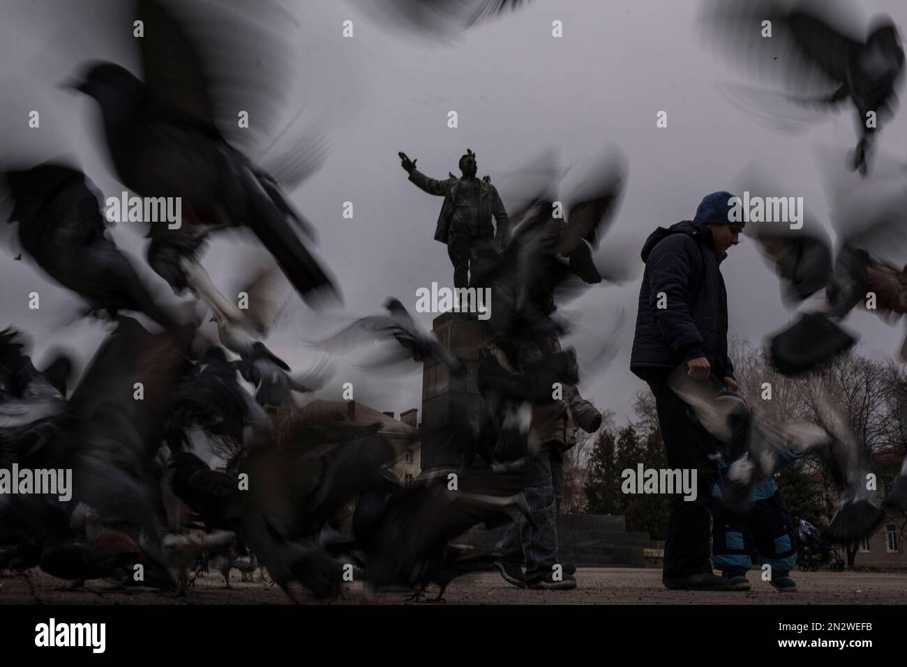 A man feeds pigeons with his son, outside the monument to Russian revolutionary Fyodor Sergeyev ...