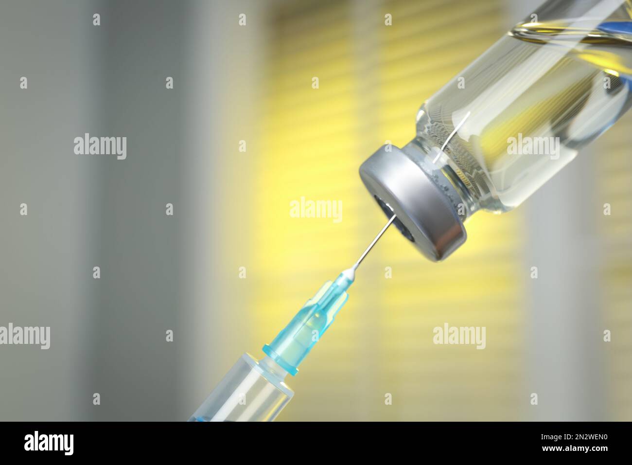 Filling syringe with medication from vial against blurred background ...