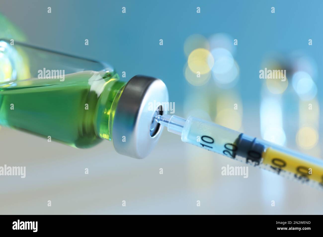 Filling syringe with medication from vial against blurred background ...