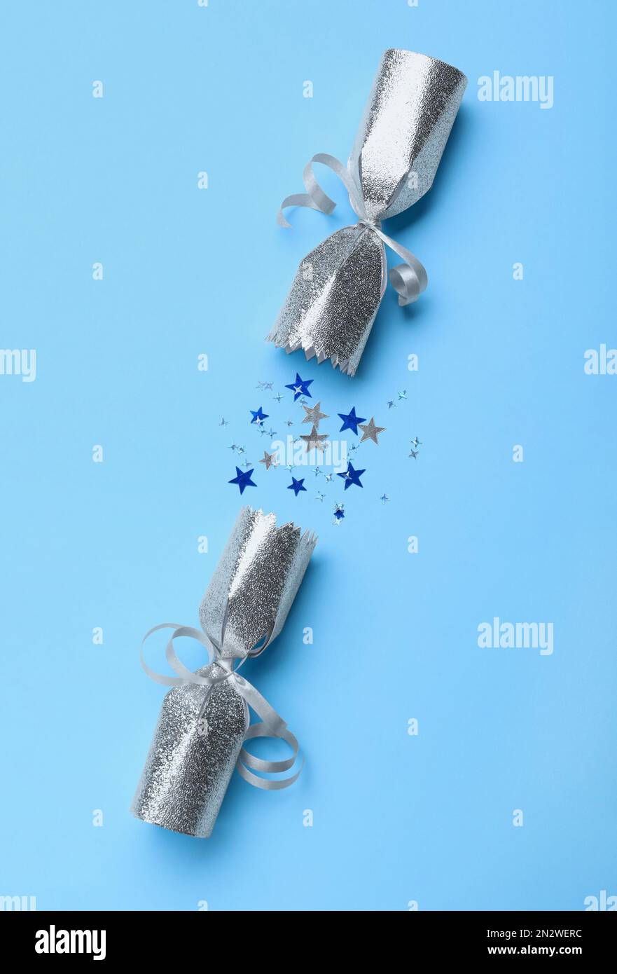 Open silver Christmas cracker with shiny confetti on light blue ...
