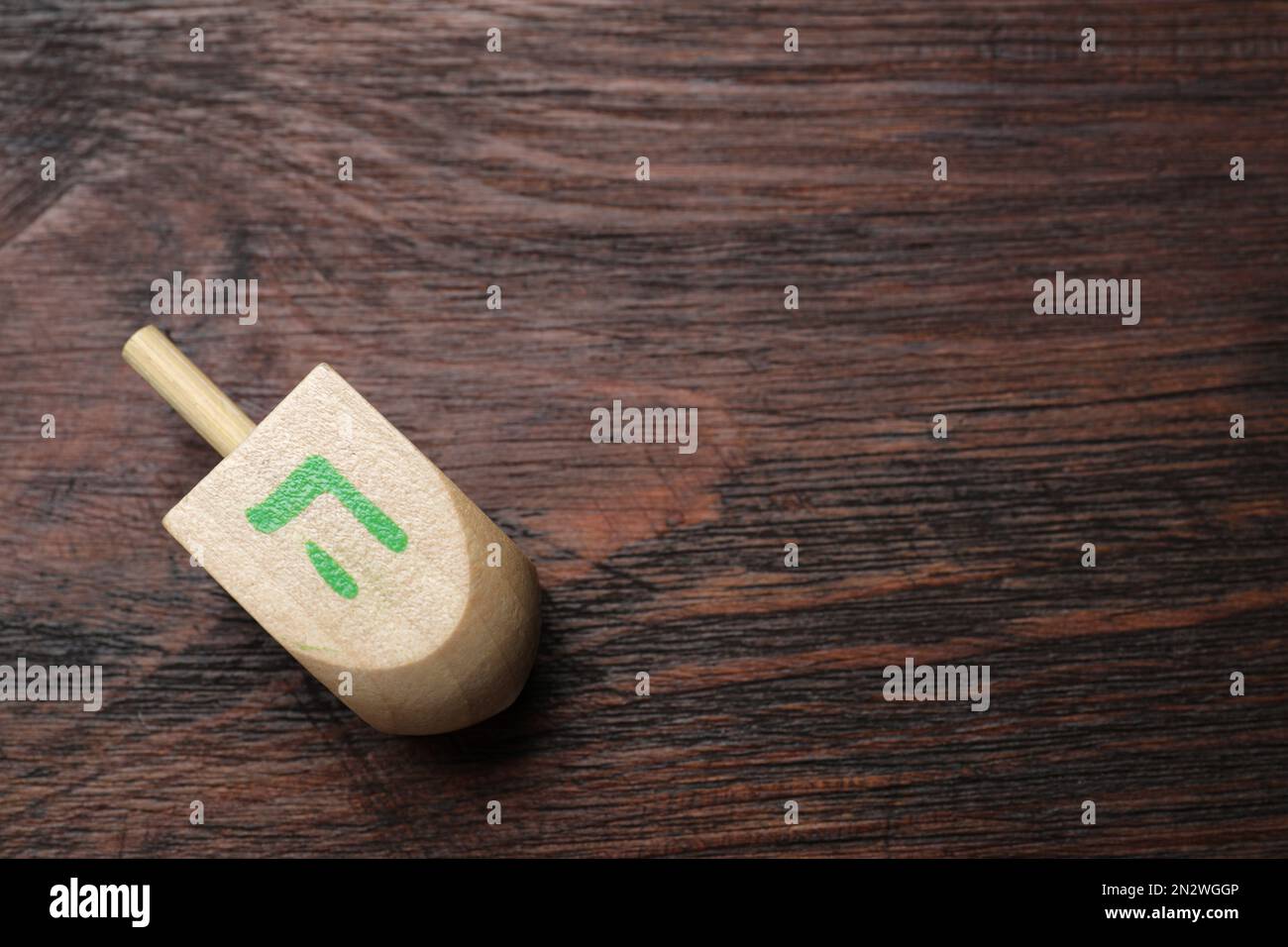 Hanukkah traditional dreidel with letter He on wooden table, top view ...
