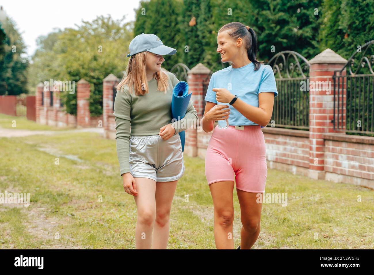 Couple of smiling female friends walking jogging in forest park relax ...