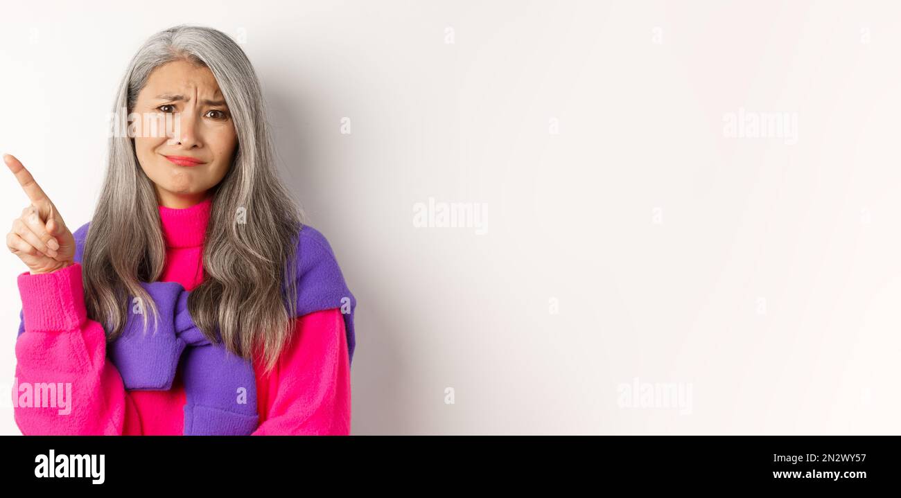 Judgy and skeptical asian senior woman grimacing displeased, pointing ...