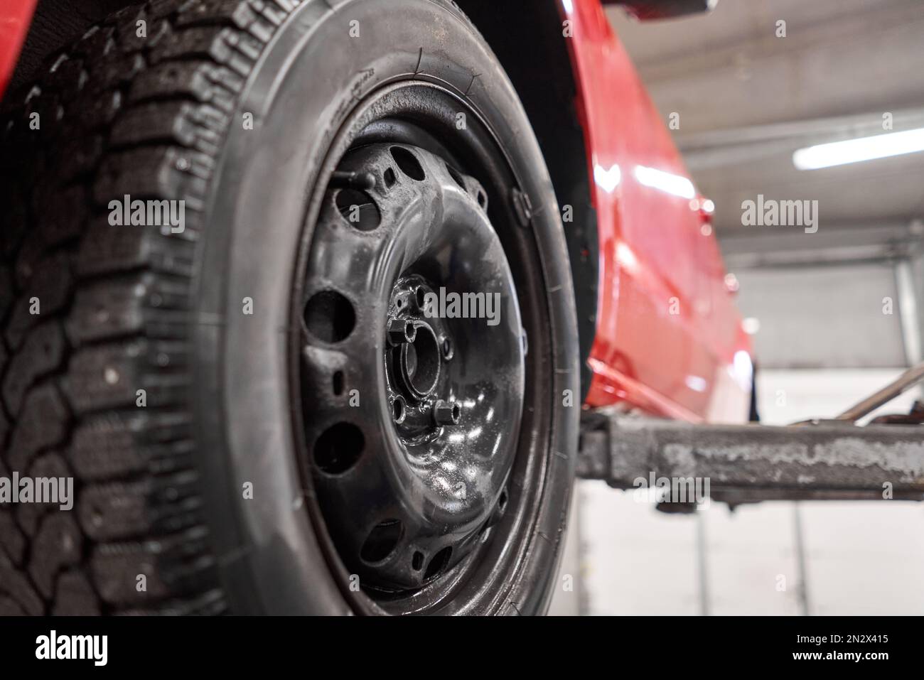 Red car on an elevator or hoist in a repair workshop or garage with ...