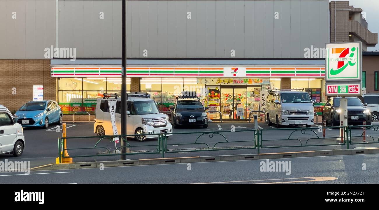 A bright storefront shot of a busy 7-Eleven convenience store at dusk ...