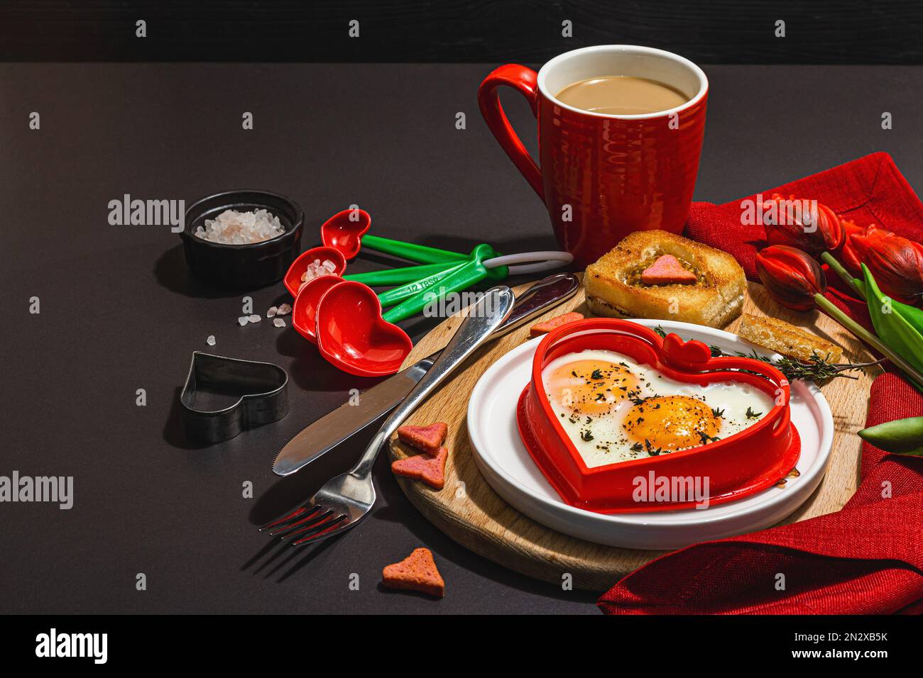 Heart-shaped fried egg served with toasted bread and spices on a plate. Romantic art food idea ...