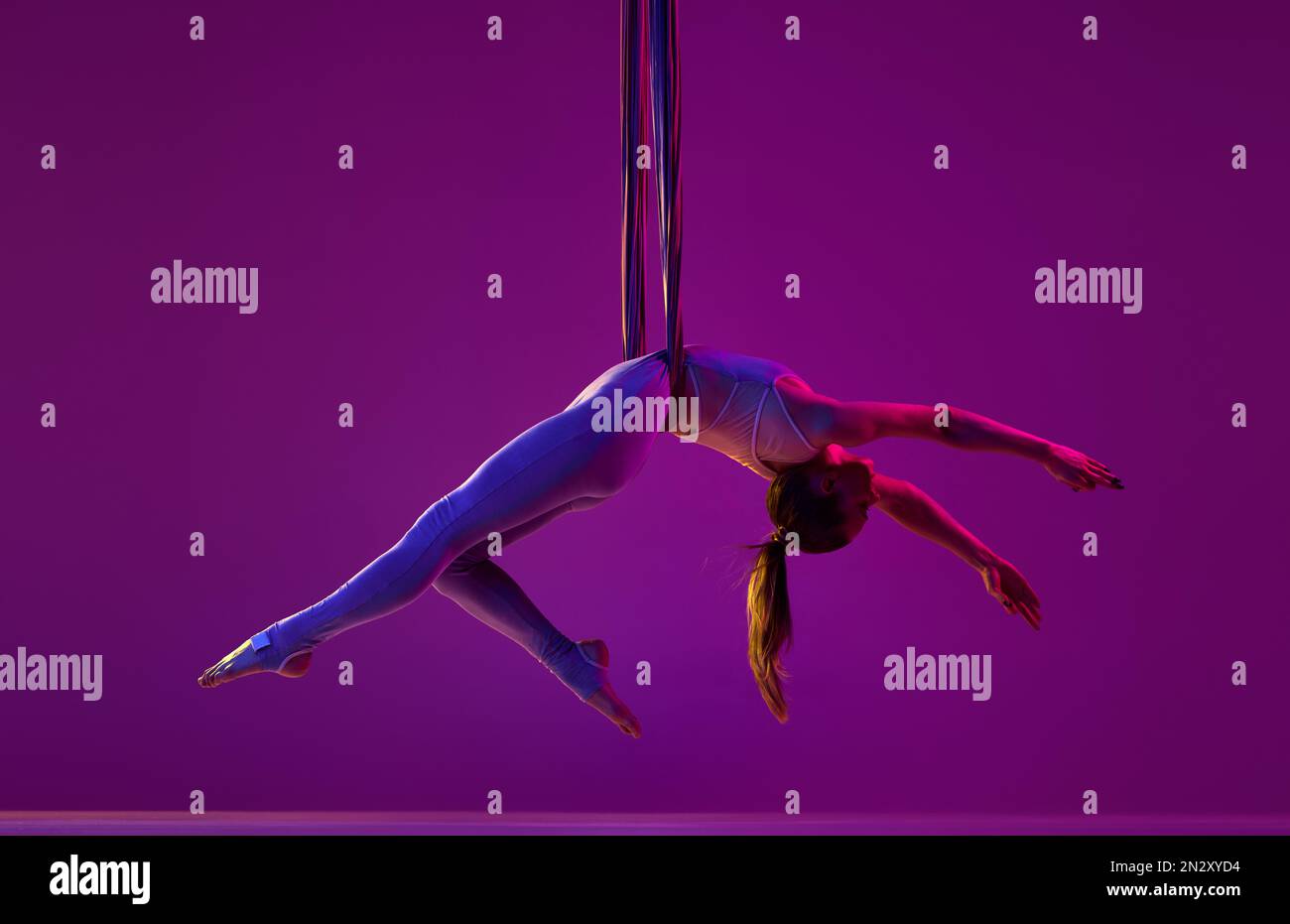 Relaxing. Young flexible girl doing aerial fly yoga, training over ...