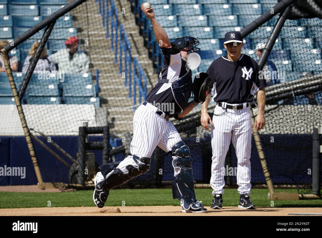 New York Yankees catcher Brian McCann, left, throws as manager Joe Girardi, right, looks on ...