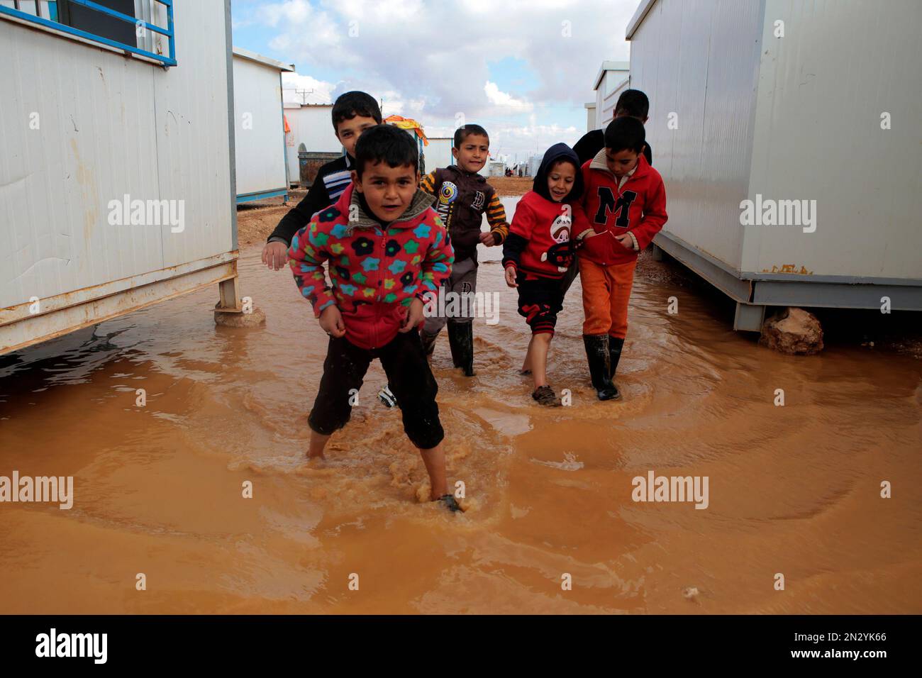 Syrian refugee children play in a puddle after recent snowfalls at ...