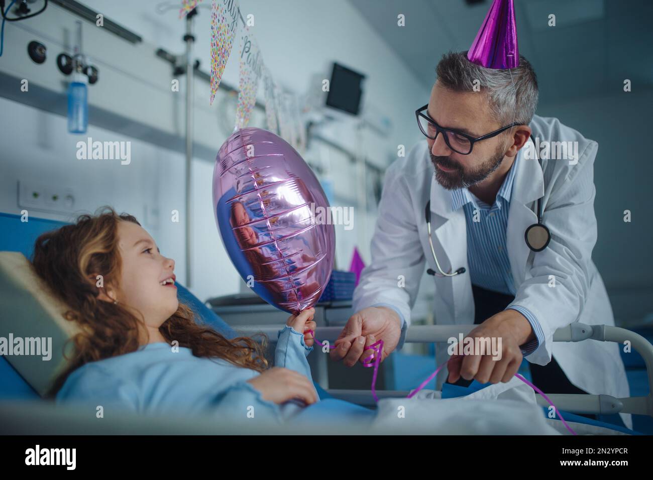 Happy doctor celebrating birthday with little girl in hospital room ...