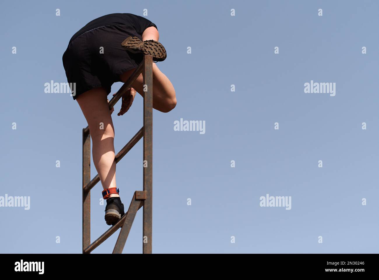 Participant in extreme obstacle race climbing over hurdle Stock Photo ...