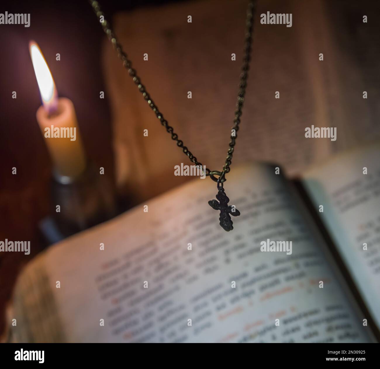 The cross on the chain hangs over the prayer book with the burning ...