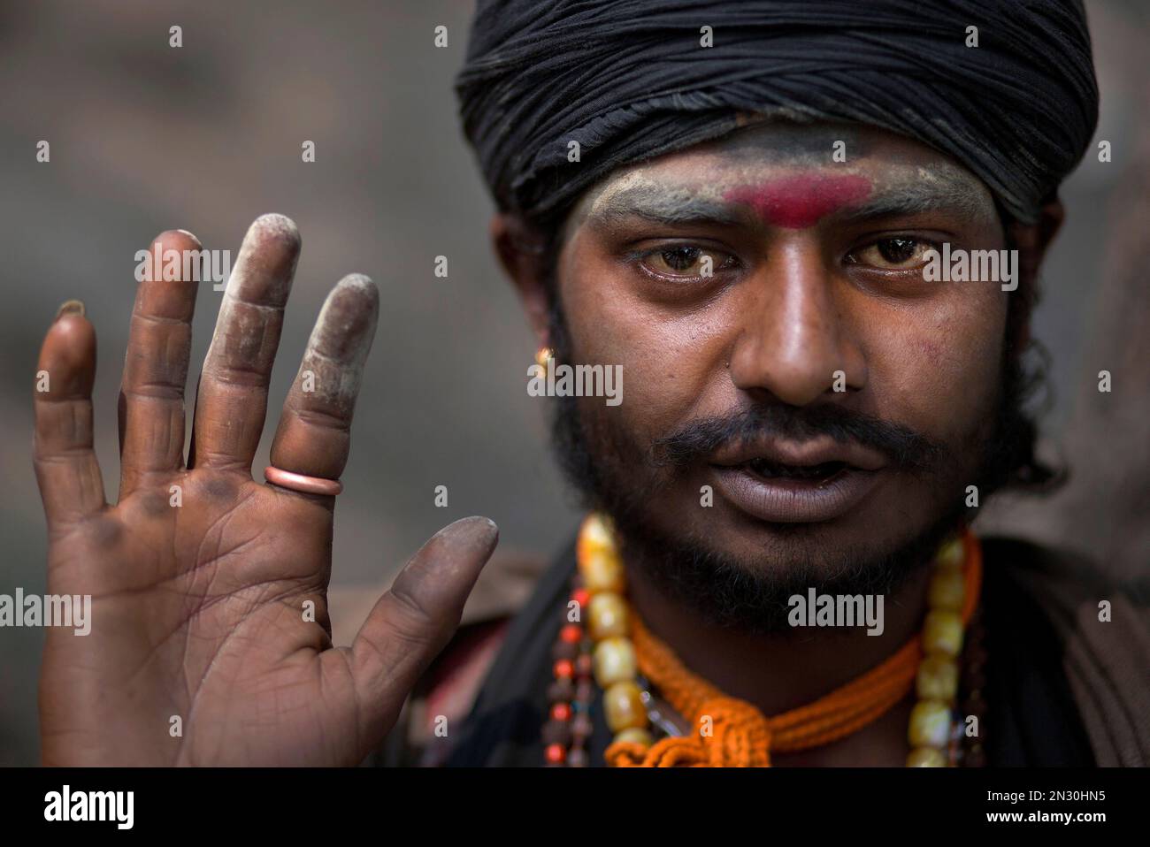 A Sadhu, or Hindu holy man, raises his hand to give blessings, near a ...