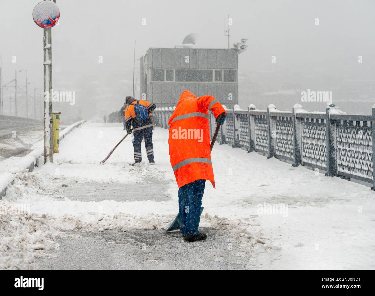 Communal services workers in uniform cleaning bridge walkway with a ...