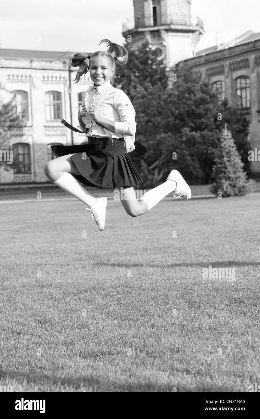 Happy energetic girl child in uniform back to school jumping for joy ...