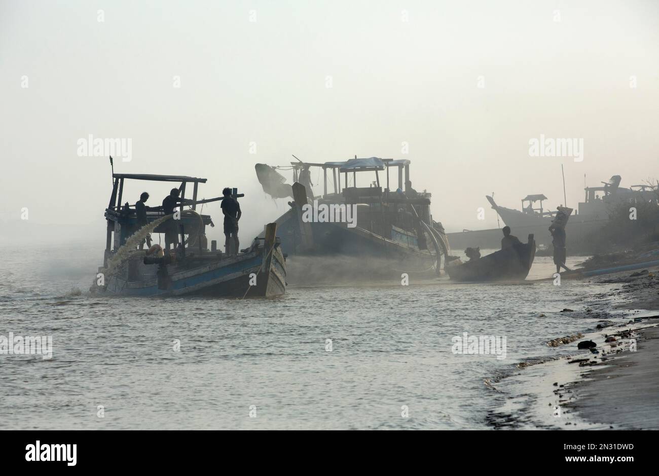 Workers load goods on a small boat as traditional wooden boats loaded ...