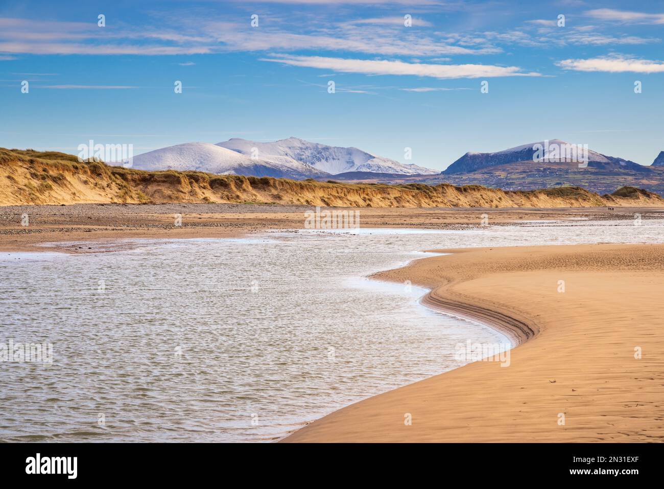 Newborough Beach and the snow covered mountains of Snowdonia in the ...