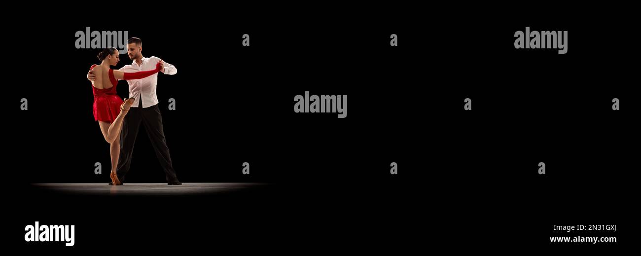 Classical performance. Young man and woman dancing tango, ballroom over black background ...