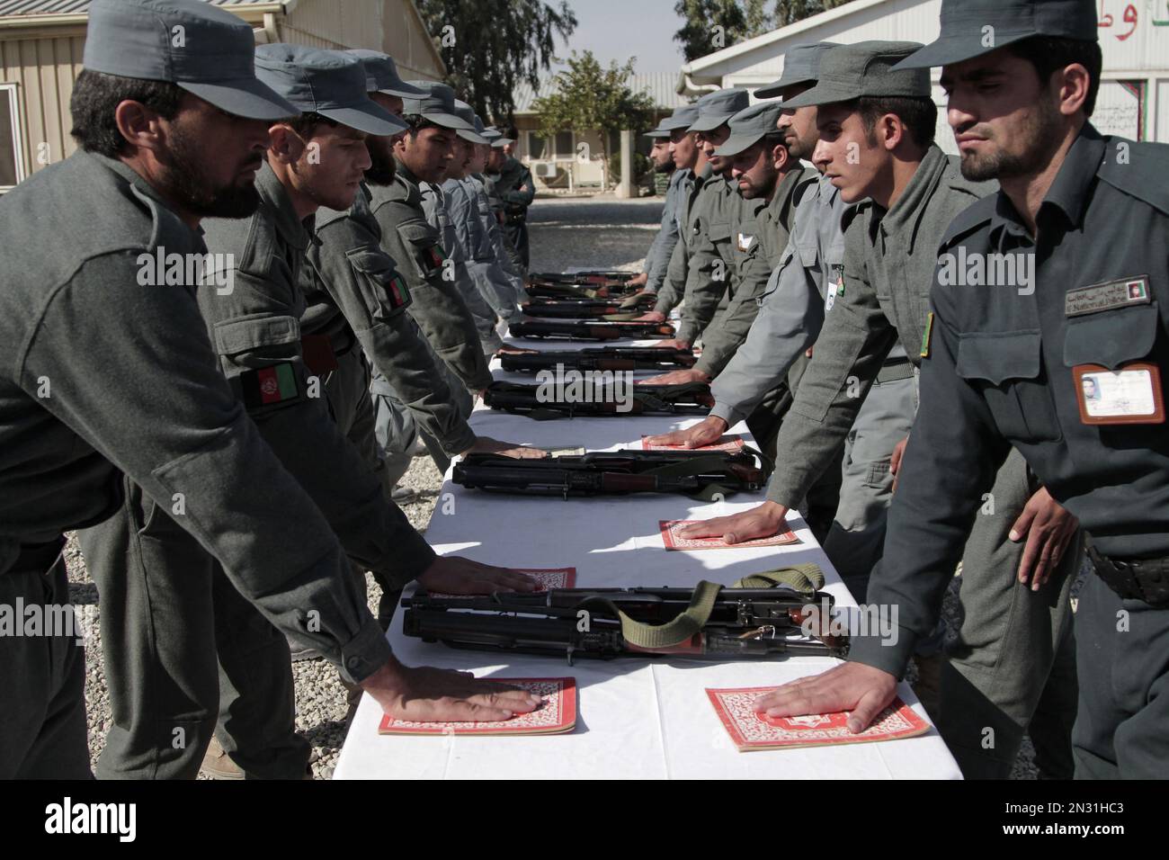 Afghan police officers take an oath while placing their hands on copies ...