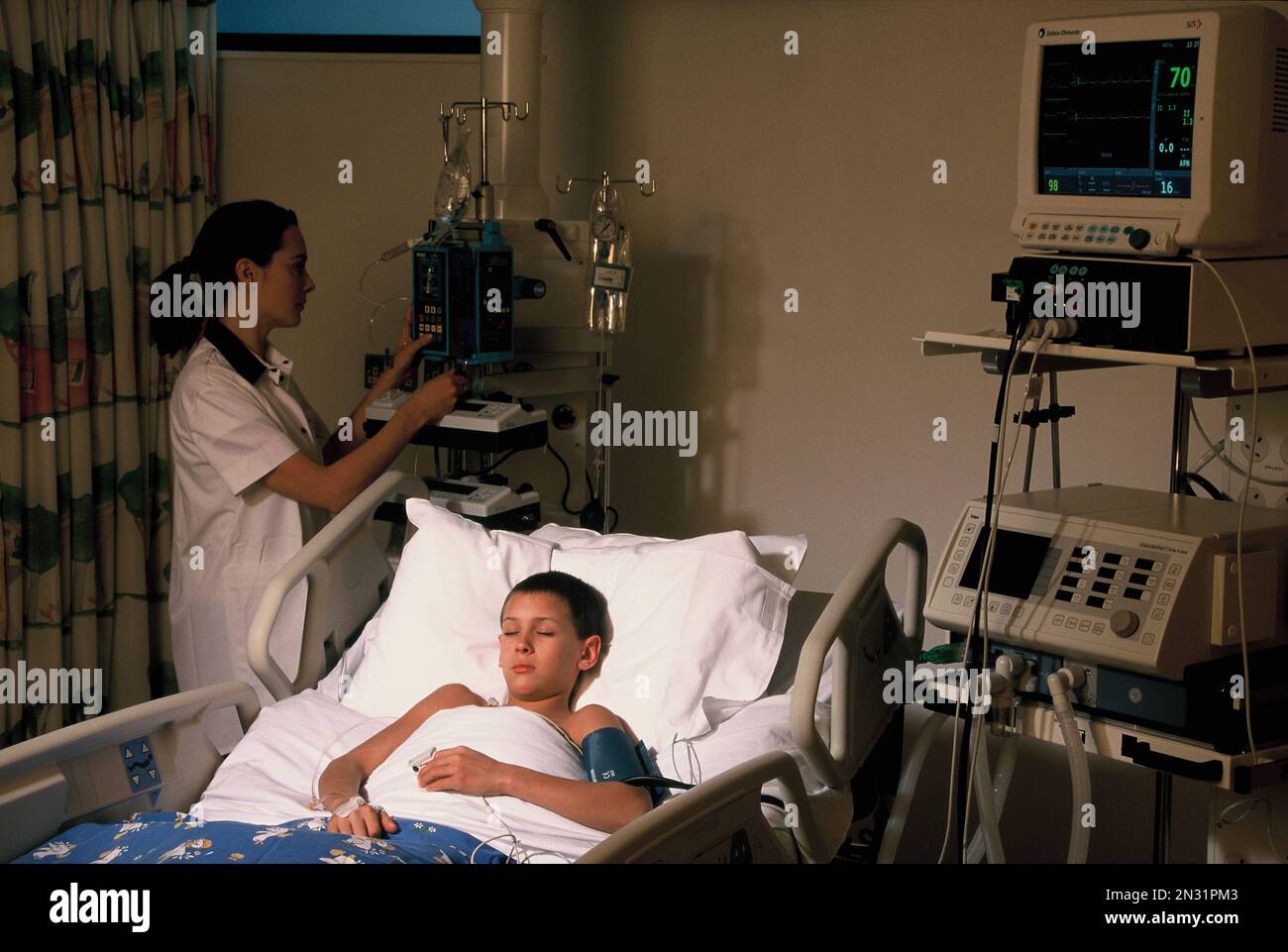 Medical nurse with young boy patient in hospital intensive care ward ...
