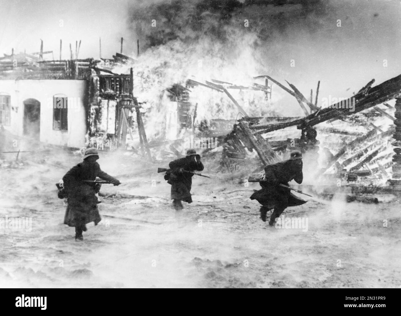 German infantry, part of a vanguard, rushing through a burning village ...