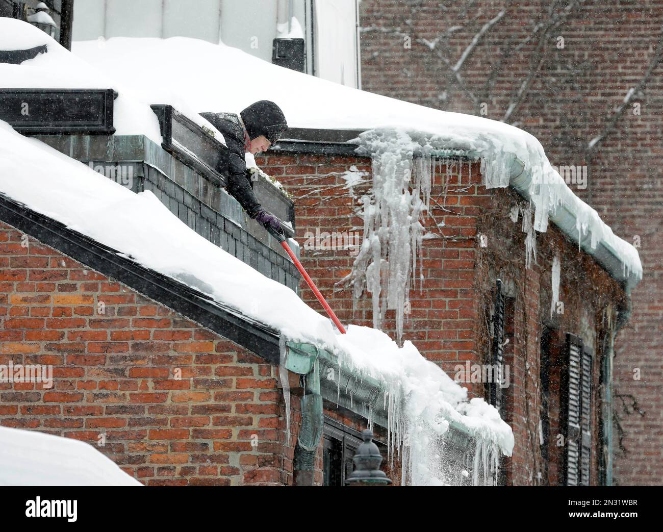 Susan Hartnett shovels snow from the roof of her Beacon Hill home ...