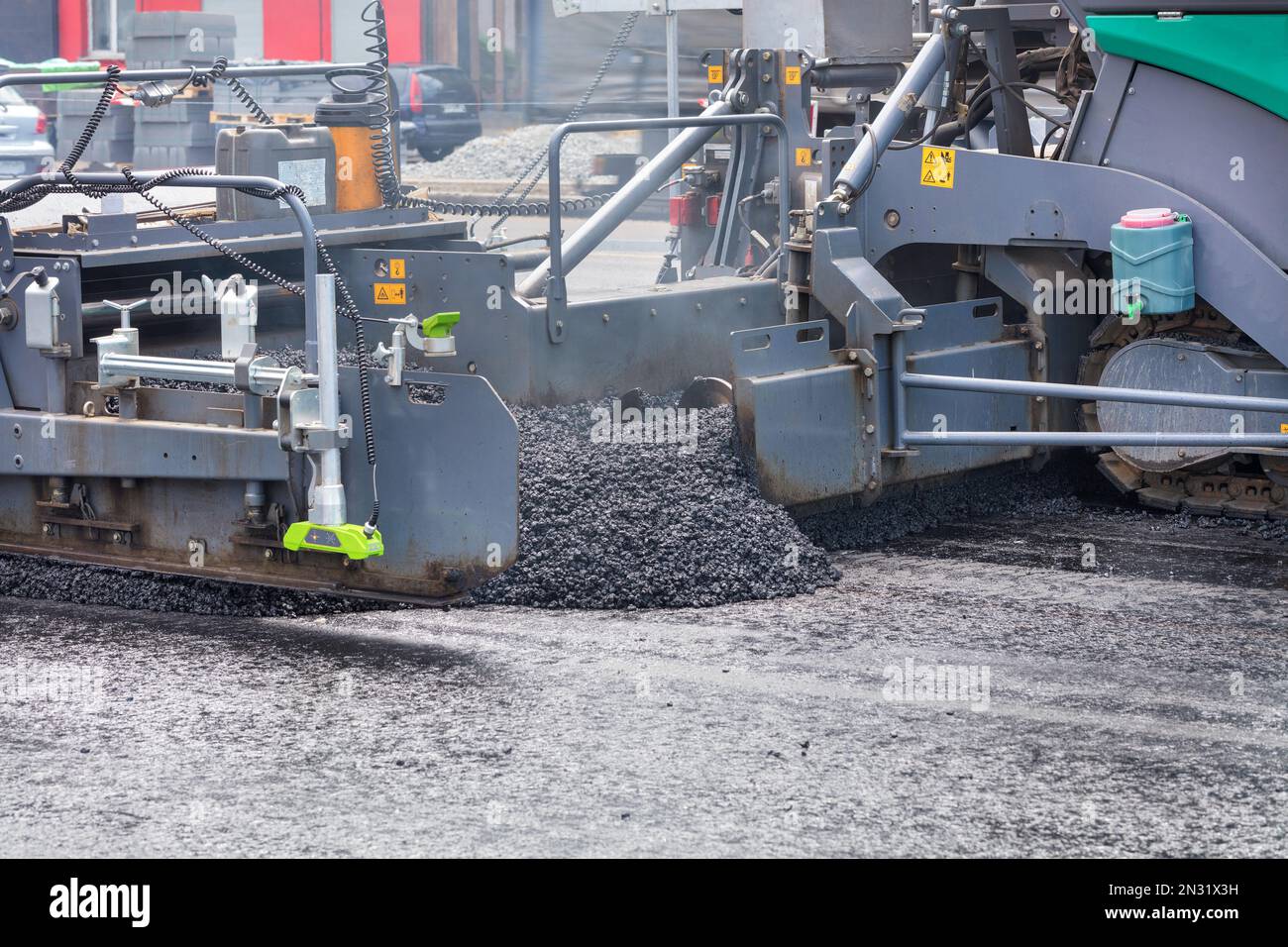 An industrial asphalt paver works on road works on a city road laying a ...