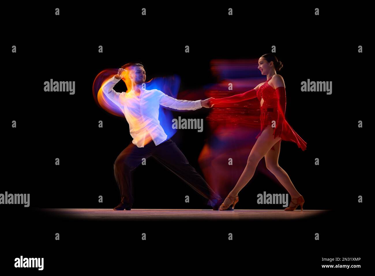Talent. Beautiful young people, man and woman dancing tango, ballroom over black background with ...